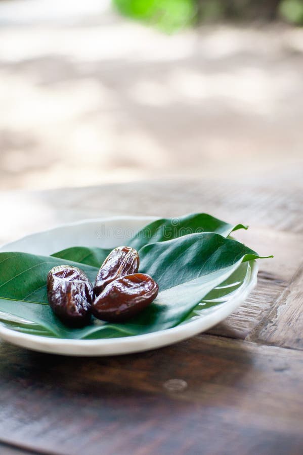 Three Dates in a White Plate with a Leaf on a Wooden Table Stock Photo ...