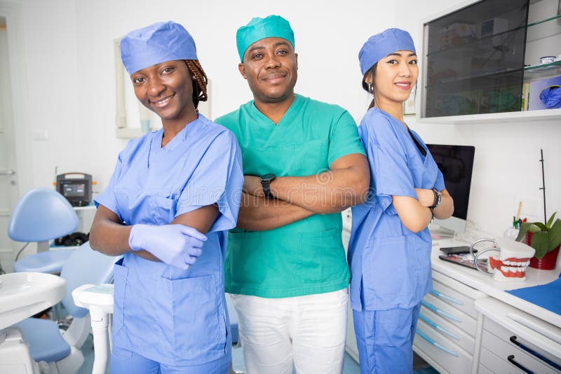 Three Dentists Pose Smiling in a Dental Office, Work in the Health ...