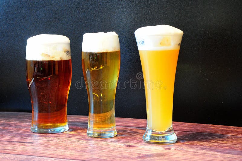 Three Different Glass Goblets with Wheat, Light and Dark Beer are on a ...