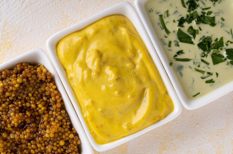 Three Different Mustard Bowls on Yellow Cement Background Stock Photo ...