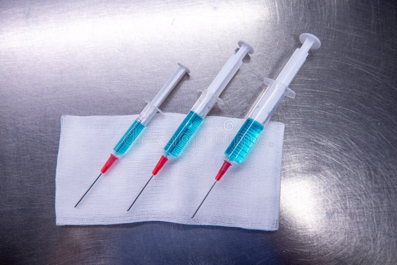 3 Differently Sized Syringes Filled with Blue Liquid Lie on a White ...