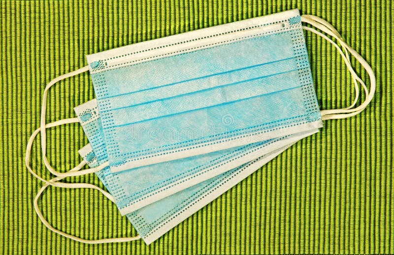 Three Disposable Protective Masks with Rubber Ear Straps on Green ...