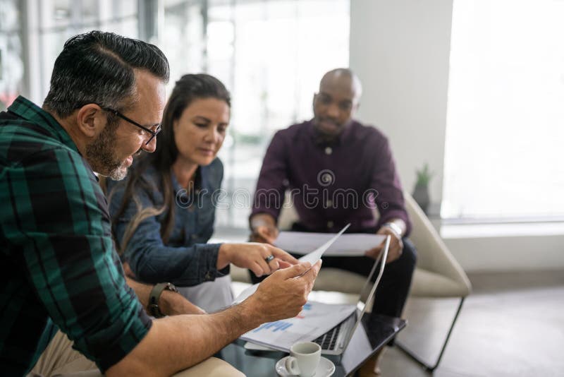 Three Diverse Businesspeople Going Over Paperwork in Bright Office Work ...
