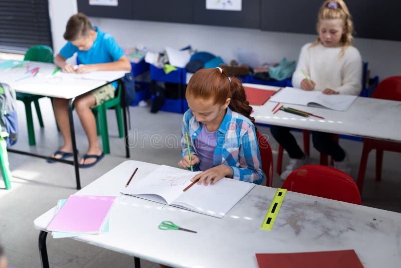 Three Diverse Elementary Schoolchildren Working at Their Desks in ...