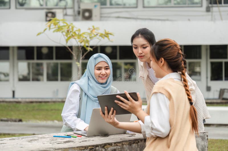 Diverse Female Students Collaborating on a Project Outdoors with a ...