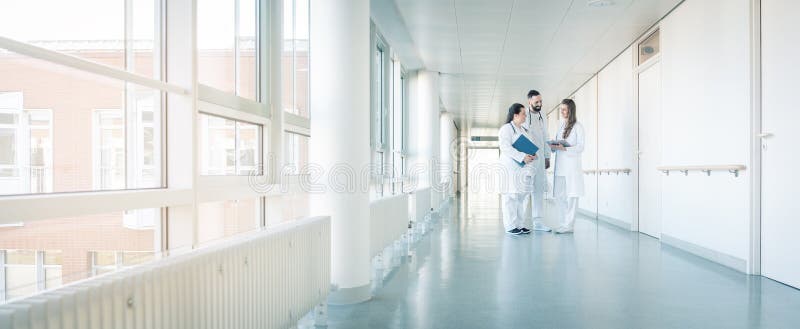 Three Doctors Walking Down a Corridor in Hospital Stock Photo - Image ...