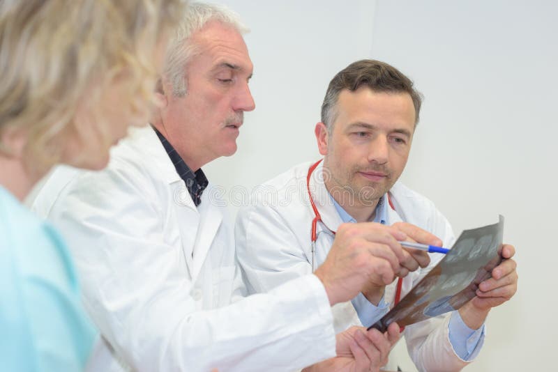 Three Doctors Looking at X-ray Stock Photo - Image of medicare, bone ...