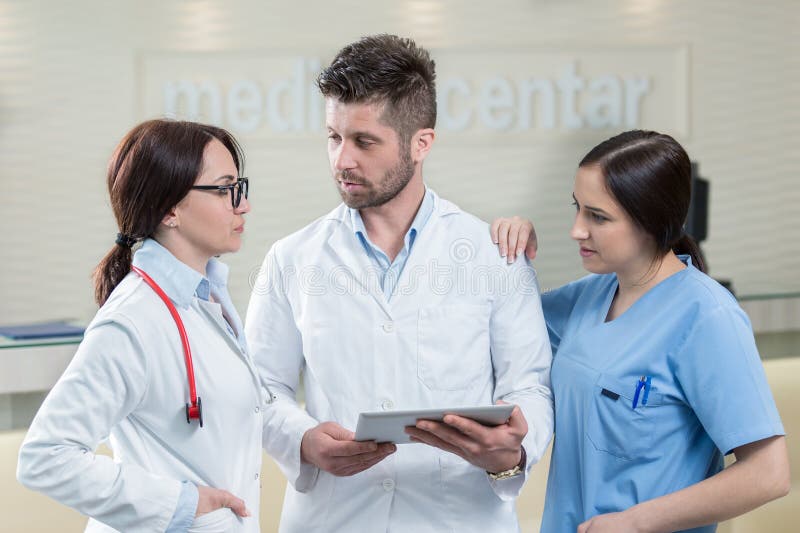 Three Doctors Using a Tablet in a Bright Office Stock Image - Image of ...