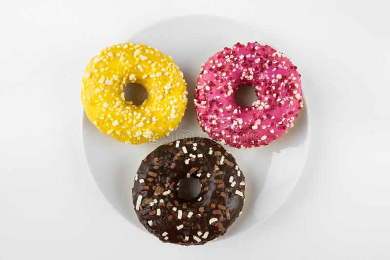 Three Donuts with Different Glazes in a White Plate on a White Wooden ...