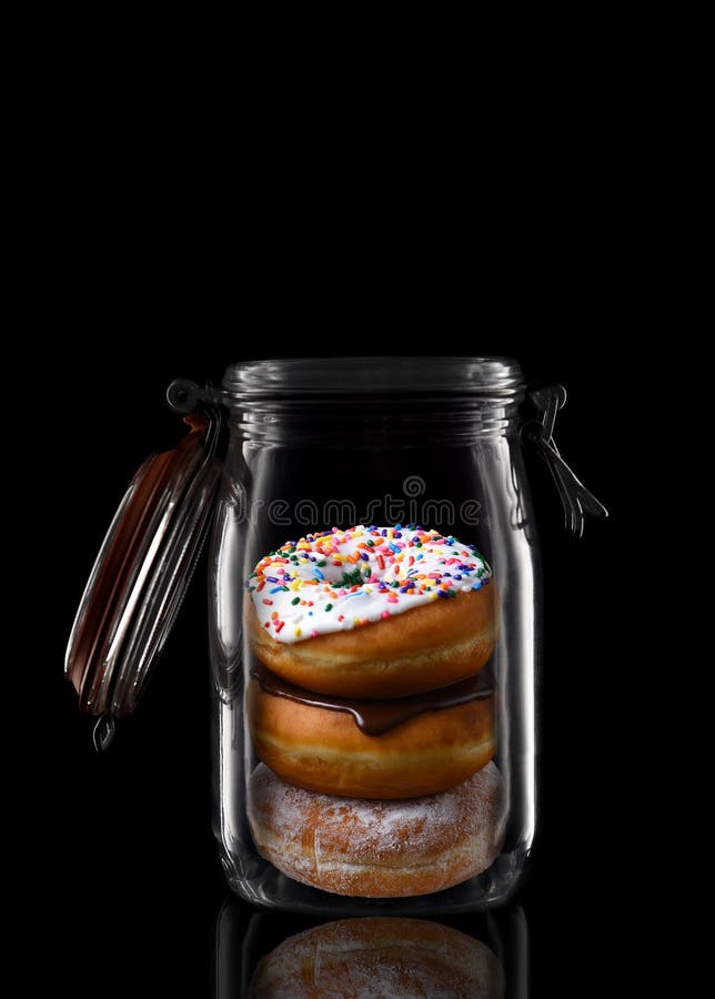 Three Donuts in a Glass Storage or Canning Jar Isolated on Black with ...