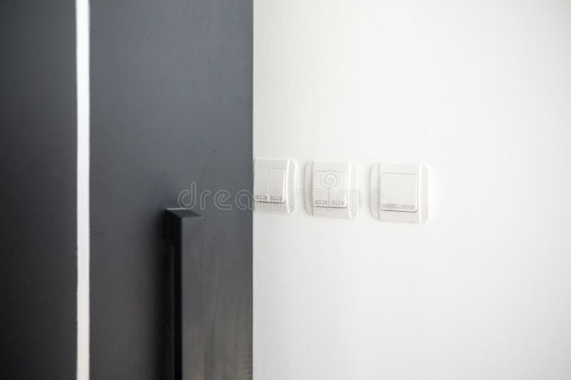 Three Double and Single Light Switch on White Wall with Black Door in ...