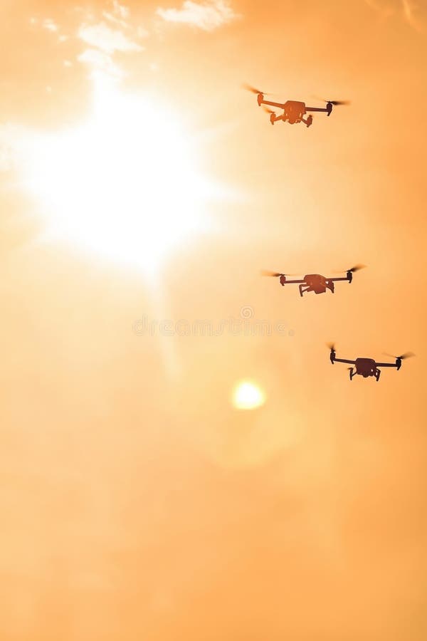 Three Drones Soaring in Orange Sky with Bright Sunlight. Stock Photo ...