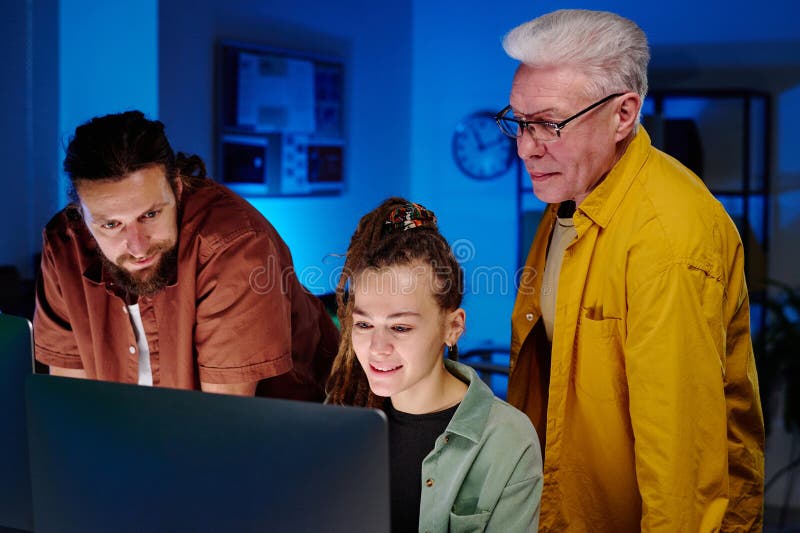 Three it Engineers Looking at Screen of Desktop Computer at Night ...