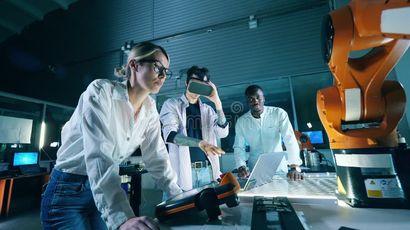 Three Engineers at Robotics Development Laboratory. Male Engineer in VR ...