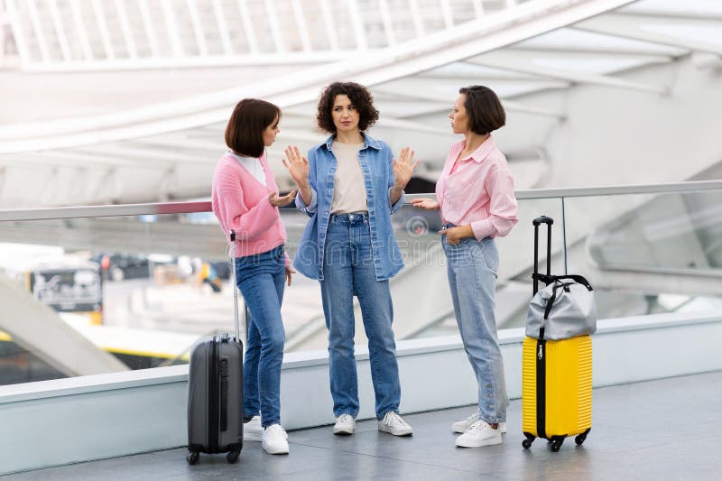 Three Female Friends Arguing while Waiting at Airport Terminal Stock ... Three Female Friends Arguing while Waiting at Airport Terminal Stock ...