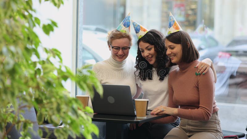 Three Female Friends are Sitting in a Coffee Shop with a Laptop and ... Three Female Friends are Sitting in a Coffee Shop with a Laptop and ...