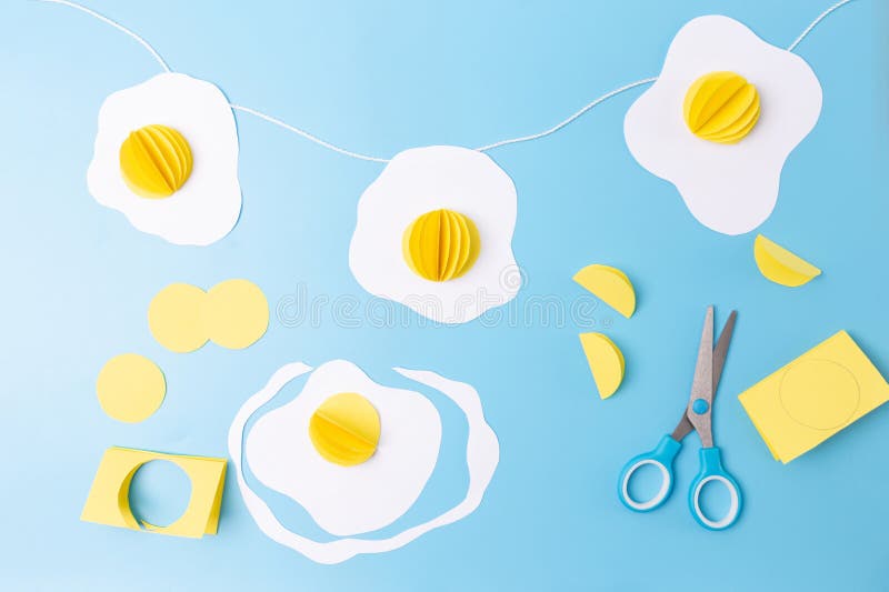 Three Fried Eggs Paper Craft Hanging from a String on a Blue Background ...