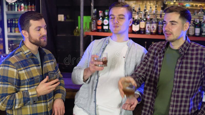 Three Friends in a Bar Chatting and Pouring Whiskey from Glasses Stock ...