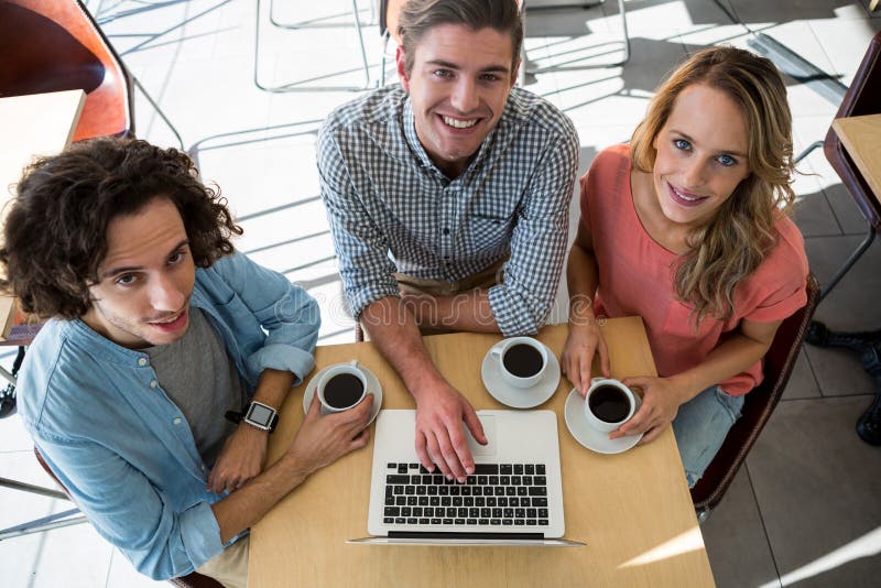 Three Friends with Coffee Cups Using a Laptop in Coffee Shop Stock ...