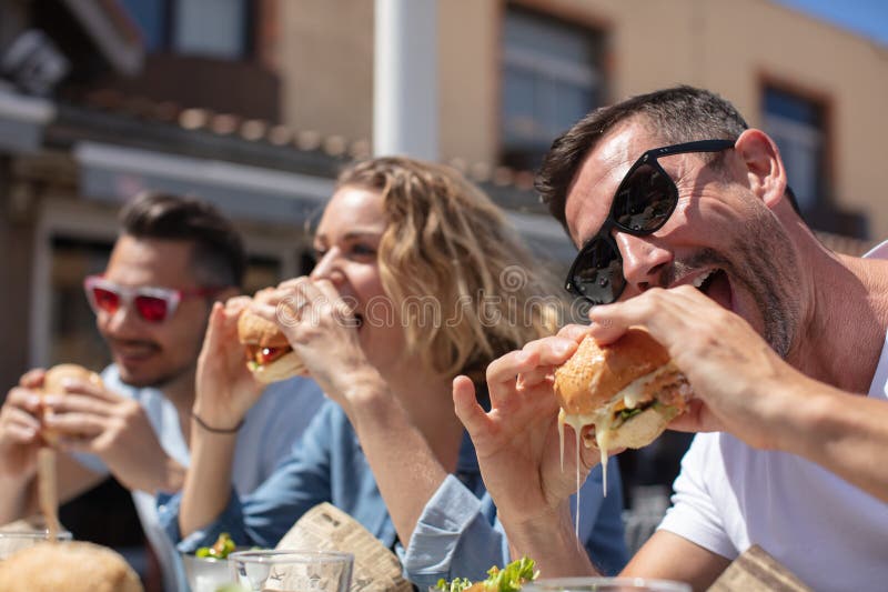 Three Friends Eating Burgers and Smiling Stock Image - Image of looking ...