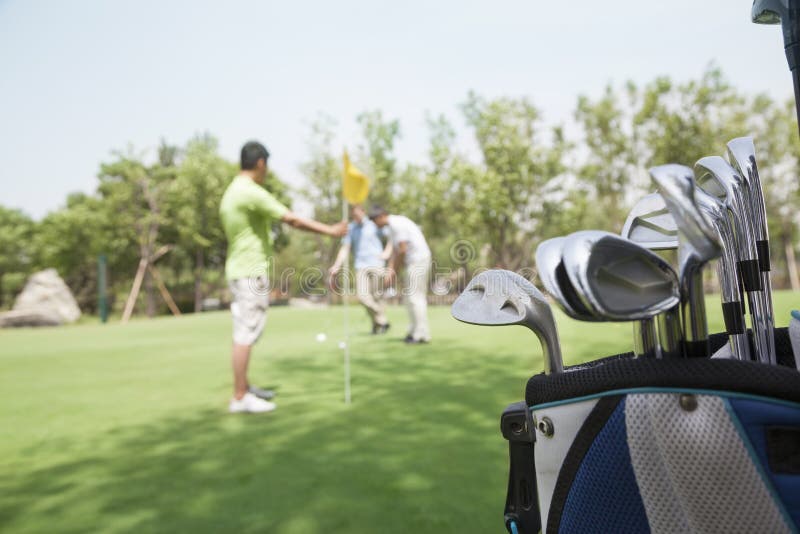 Three Friends Playing Golf on the Golf Course, Focus on the the Caddy ...