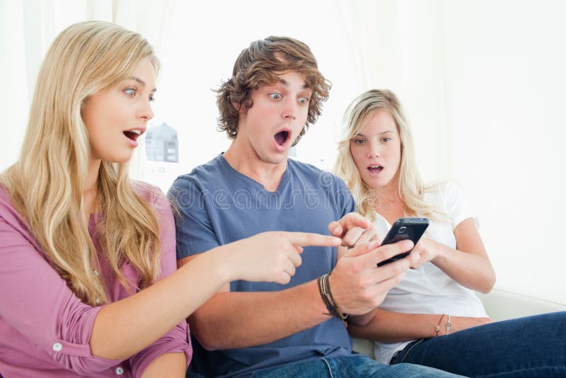 Three Friends Shocked at the Message on the Phone Stock Image - Image ...