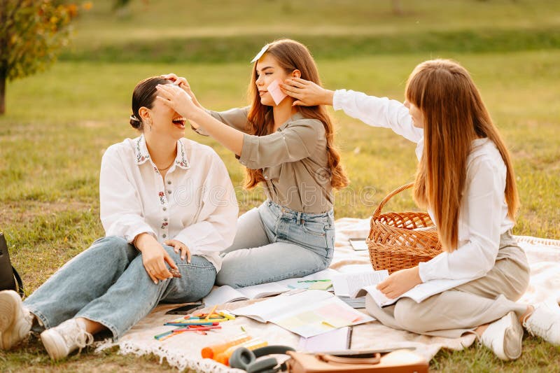 Three Friends Study Together in a Park while Having Fun with Sticky ...