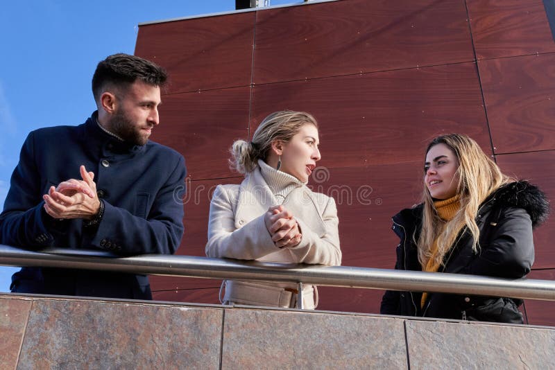 Three Friends Talking Cordially. Leaning on a Railing. Friendship ...