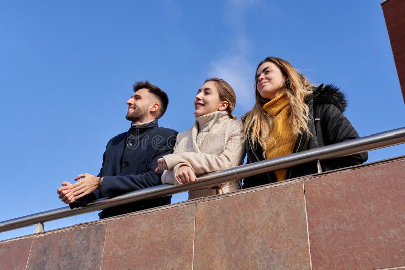 Three Friends Talking Cordially. Leaning on a Railing. Friendship ...
