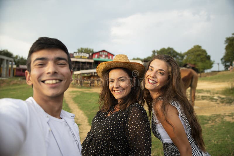 Three Friends Using Smart Phone for Photograph with the Horses in the ...