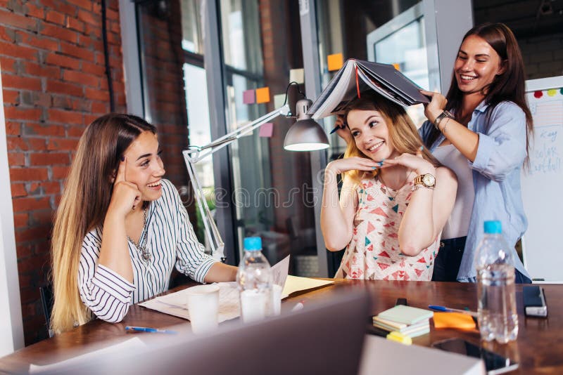 Three Funny Young Students Having Fun while Sitting at Desk Preparing ...