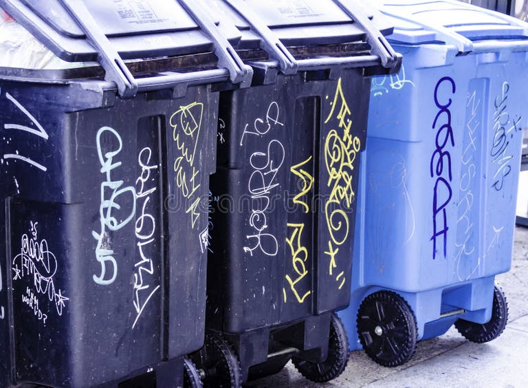 Three Garbage Cans with Graffiti are Lined Up Side by Side on a ...