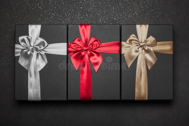 Three Gift Boxes with a Red Gray and Gold Ribbon and Large Bows on Dark ...
