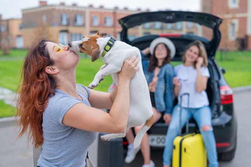 Three Girlfriends Travel by Car with a Dog and Load Suitcases into the ...