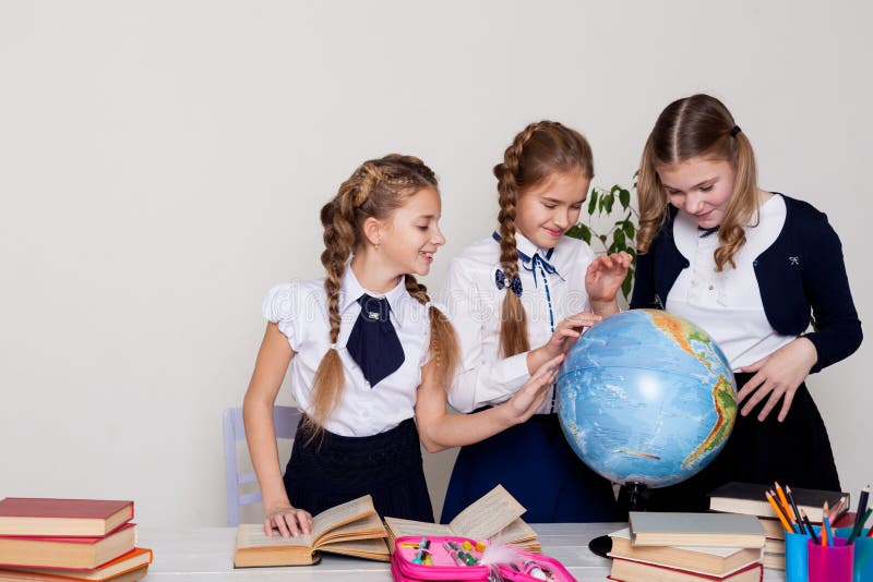 Three Girls with Books and a Globe in Class at the Desk at School Stock ...