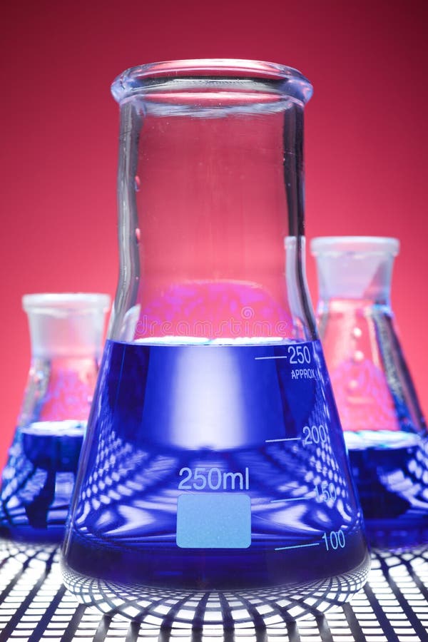 Three Glass Flasks Placed in a Laboratory Table with Blue Liquid Stock ...