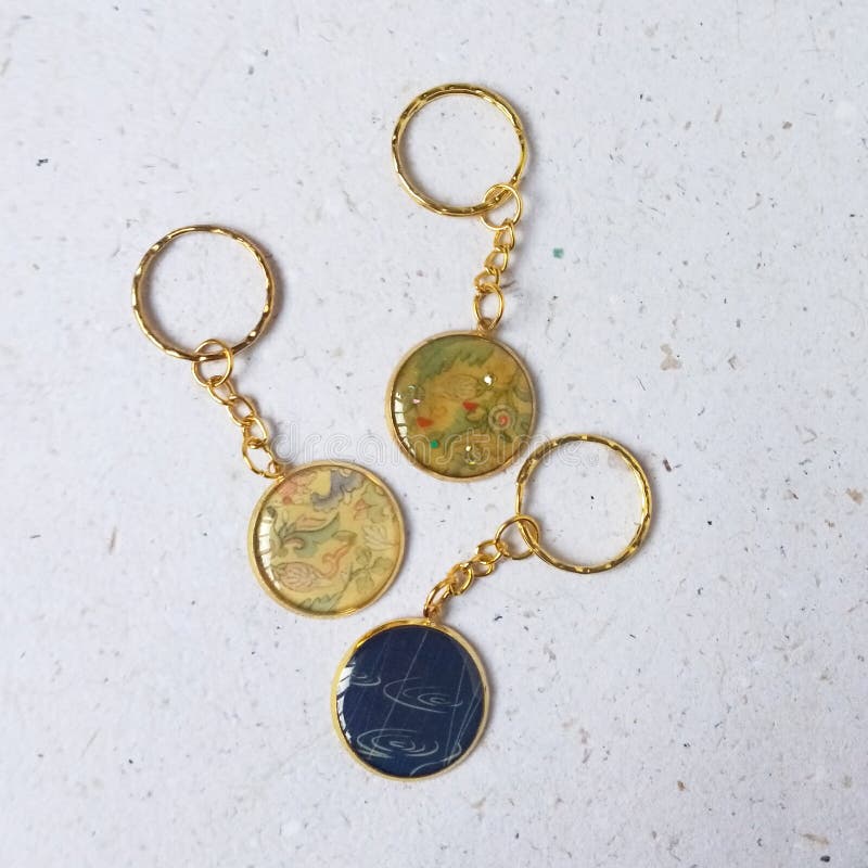 Three Gold Keychains with a Blue and Green Label and a Blue and Gold ...