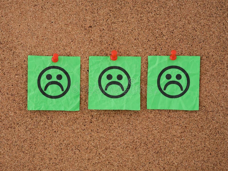 Three Green Paper Notes with Sad Faces on Them Pinned To a Corkboard ...