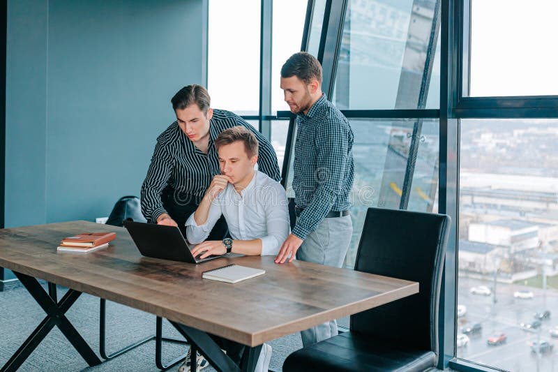Three Guys in the Office Collaborating on a Project, with Their Laptops ...