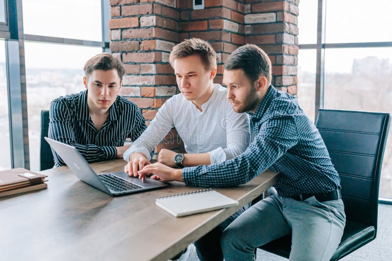 Three Guys Working on Their Laptops, with a Trainer Providing Support ...