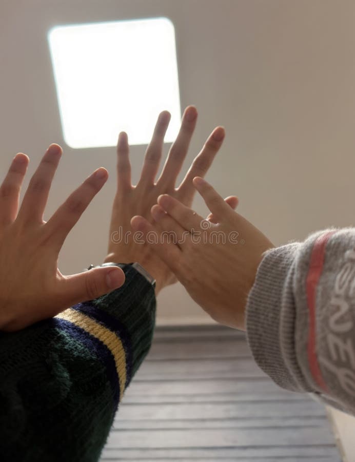 Three Hands Reaching Up Toward a Square Light Source, Captured from a ...