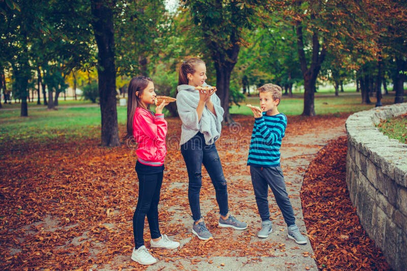 Three Happy Children Talking and Eating Pizza Outdoors Stock Image ...