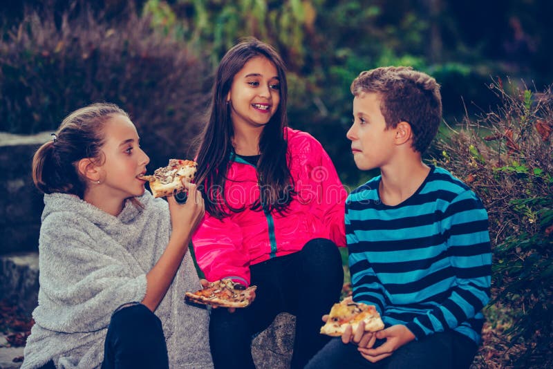 Three Happy Children Talking and Eating Pizza Outdoors Stock Photo ...