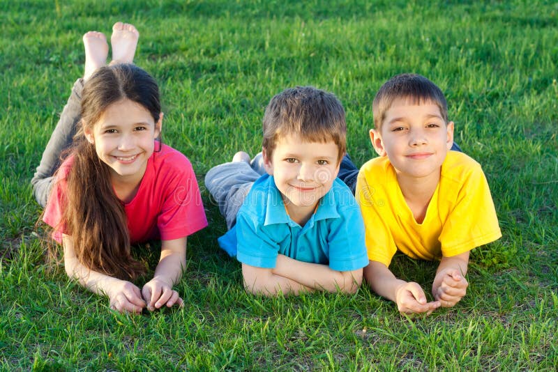Three Happy Kids Lying on the Field Stock Image - Image of green, child ...