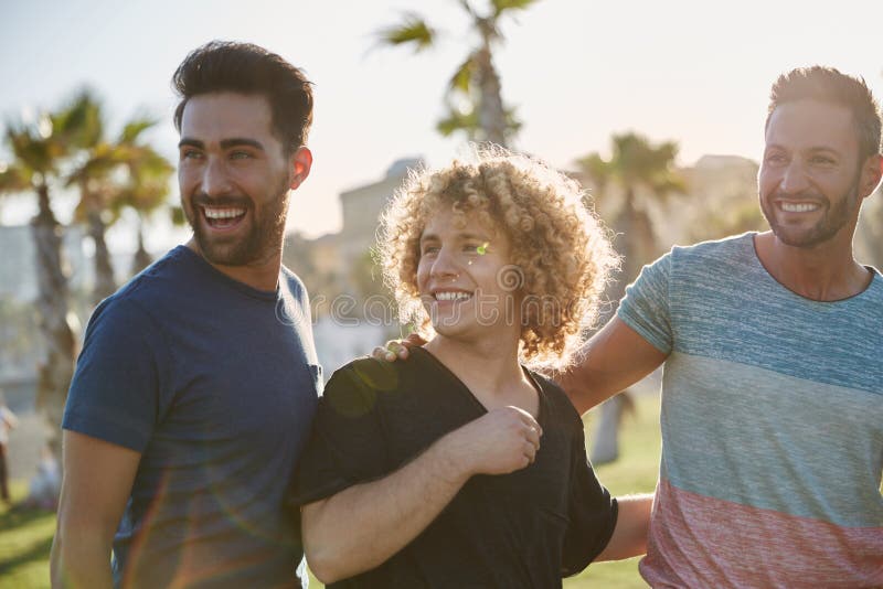 Three Happy Men Standing Outside Together Looking Away Stock Photo ...