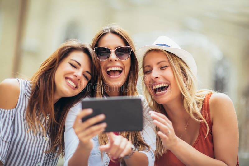 Three Happy Smiling Female Friends Sharing a Tablet Computer As they ...