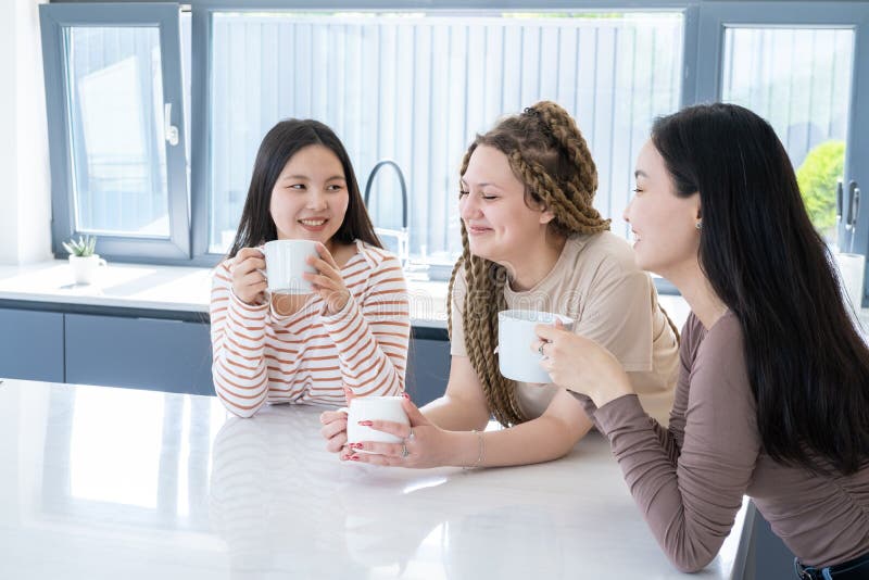 Three Happy Young Diversity Girlfriends Drinking Tea, Talking, Having ...