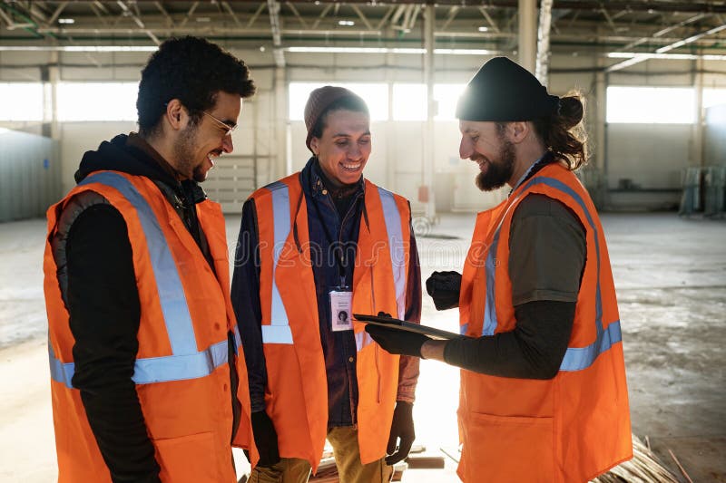 Three Happy Young Male Workers of Warehouse Discussing Presentation ...