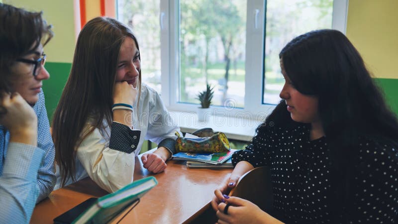 Three High School Students Collaborate at a Desk, Discussing and ...