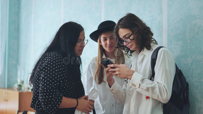 Three High School Students Discussing Something on a Smartphone. Stock ...